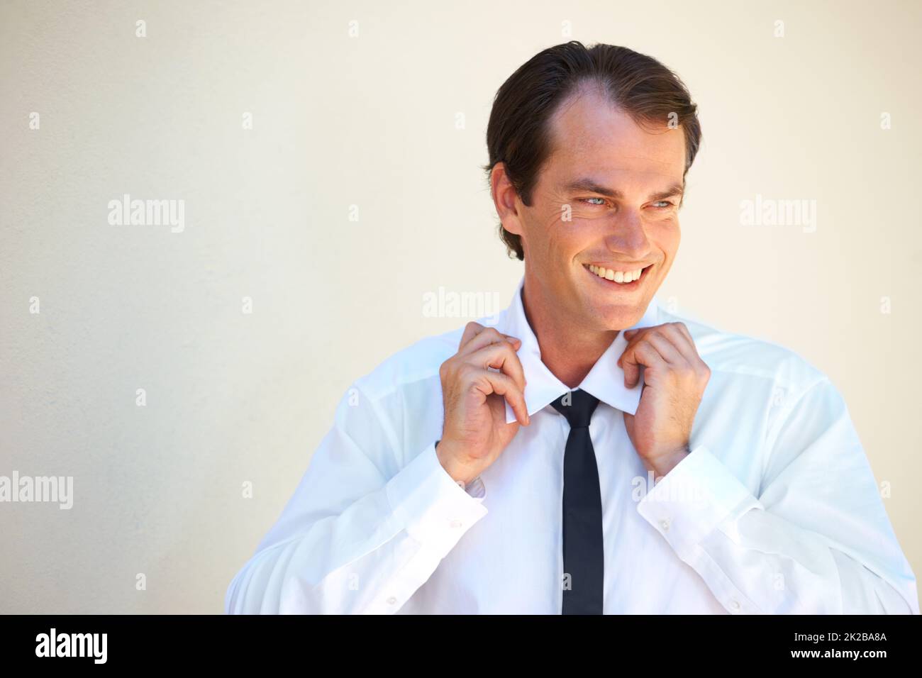 Getting ready for work. A handsome man adjusting his tie and collar ...