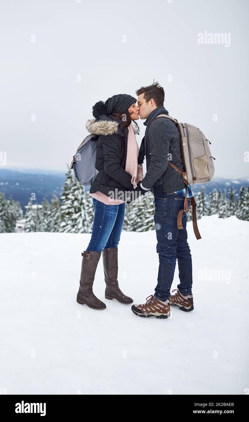 Our love is one great adventure. Shot of a couple kissing while spending the day in the snow ...