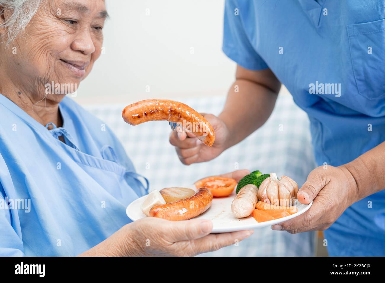 Asian senior or elderly old lady woman patient eating breakfast sausage ...