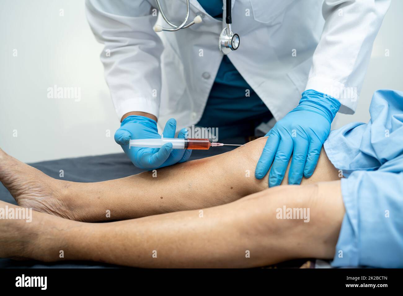 Asian doctor inject Hyaluronic acid platelet rich plasma into the knee of senior woman to walk ...