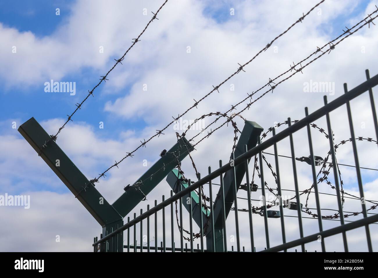 Barbed wire against a cloudy sky on a big fence at a border Stock Photo ...
