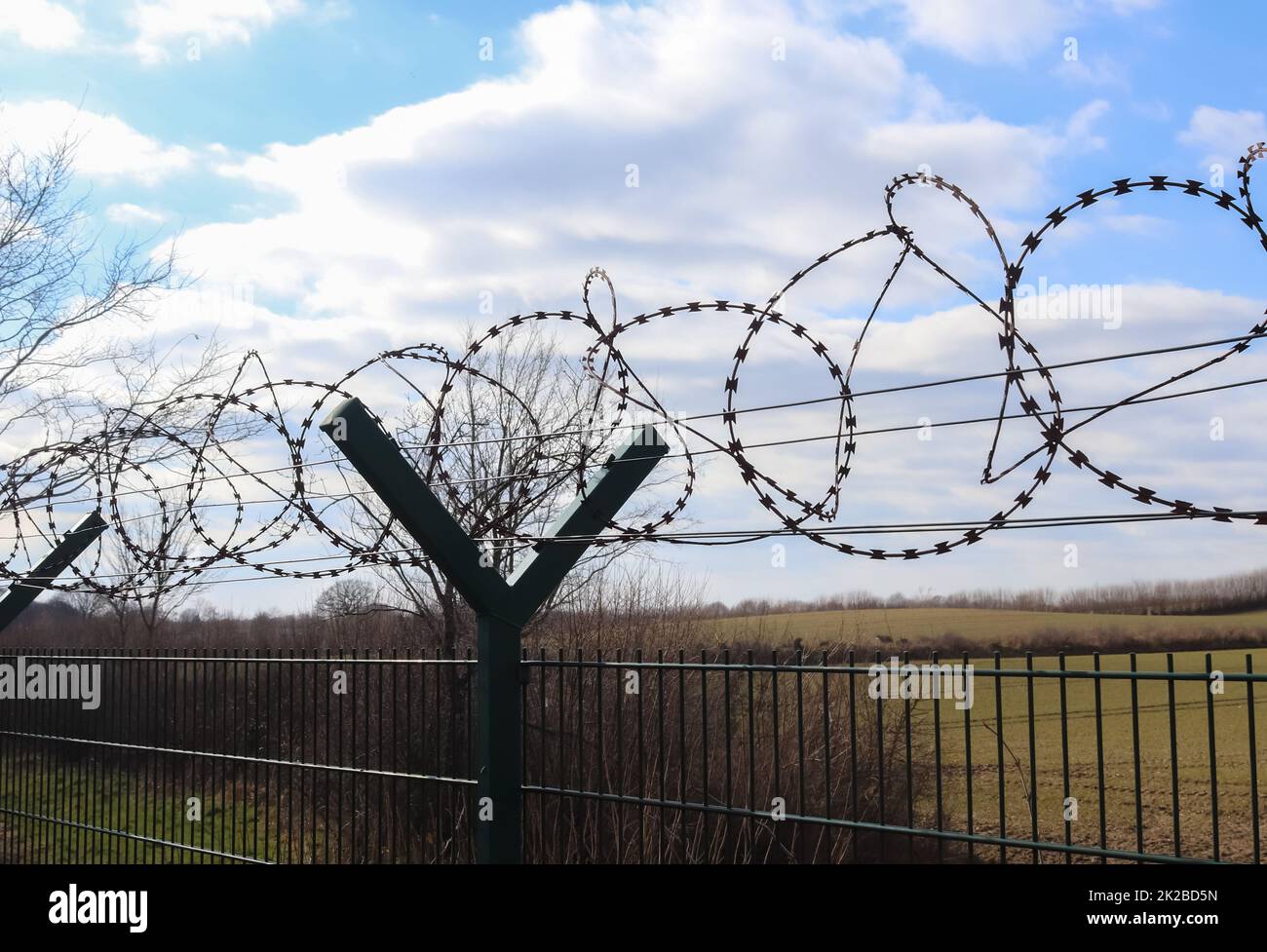 Barbed wire against a cloudy sky on a big fence at a border Stock Photo ...