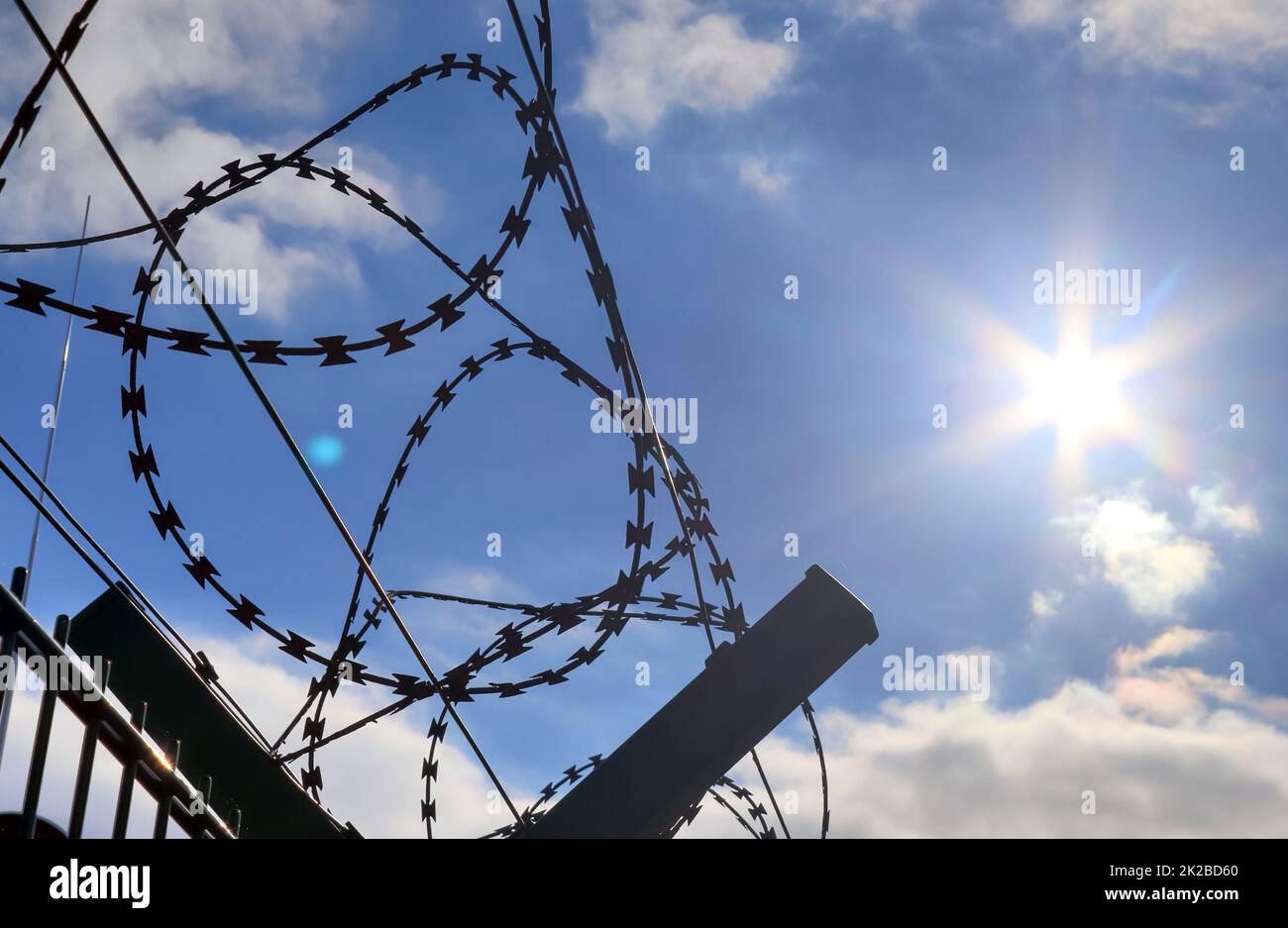 Barbed wire against a cloudy sky on a big fence at a border Stock Photo ...