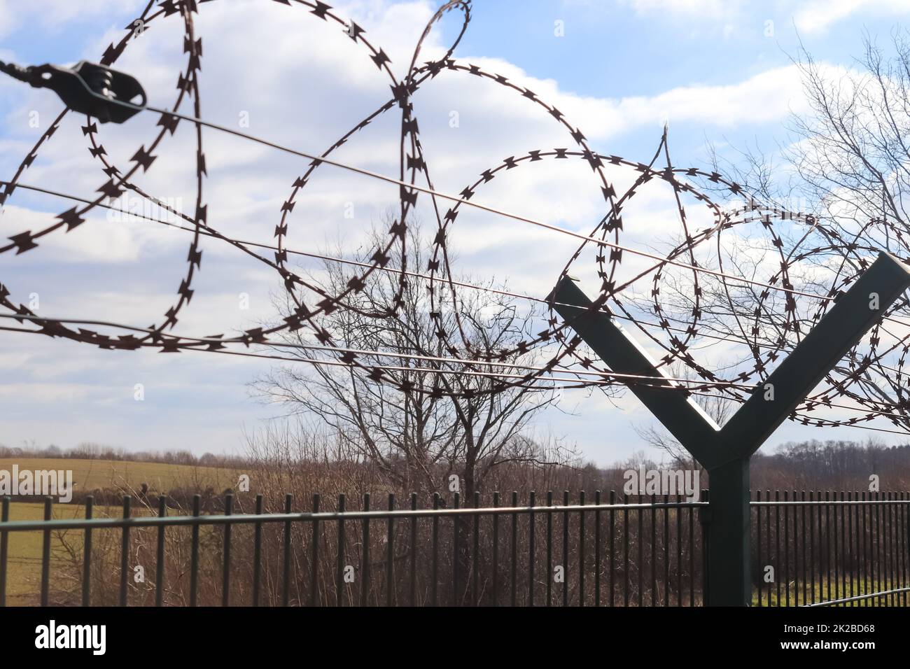 Barbed wire against a cloudy sky on a big fence at a border Stock Photo ...