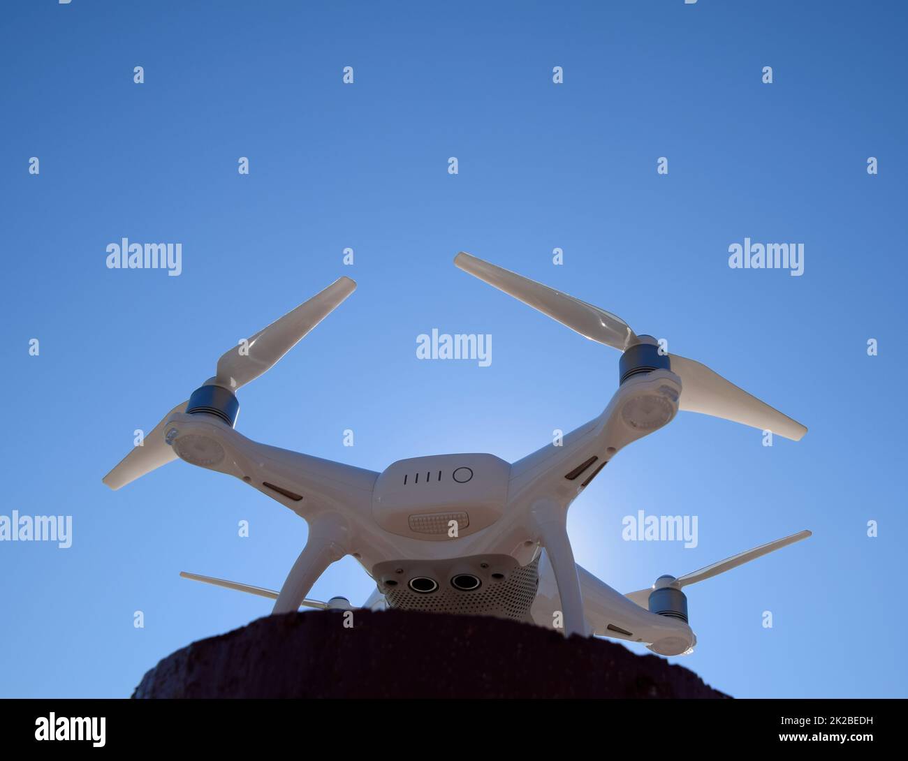 Quadrocopter Phantom 4 against the blue sky in the sun. Backlight. Dron ...