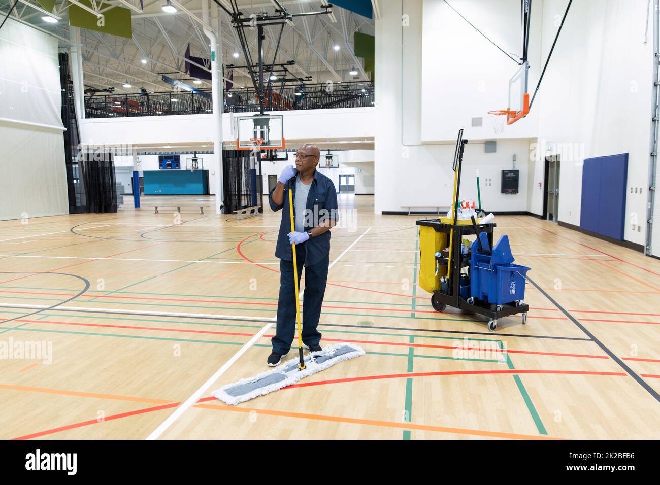 Cleaner working in school gymnasium Stock Photo - Alamy