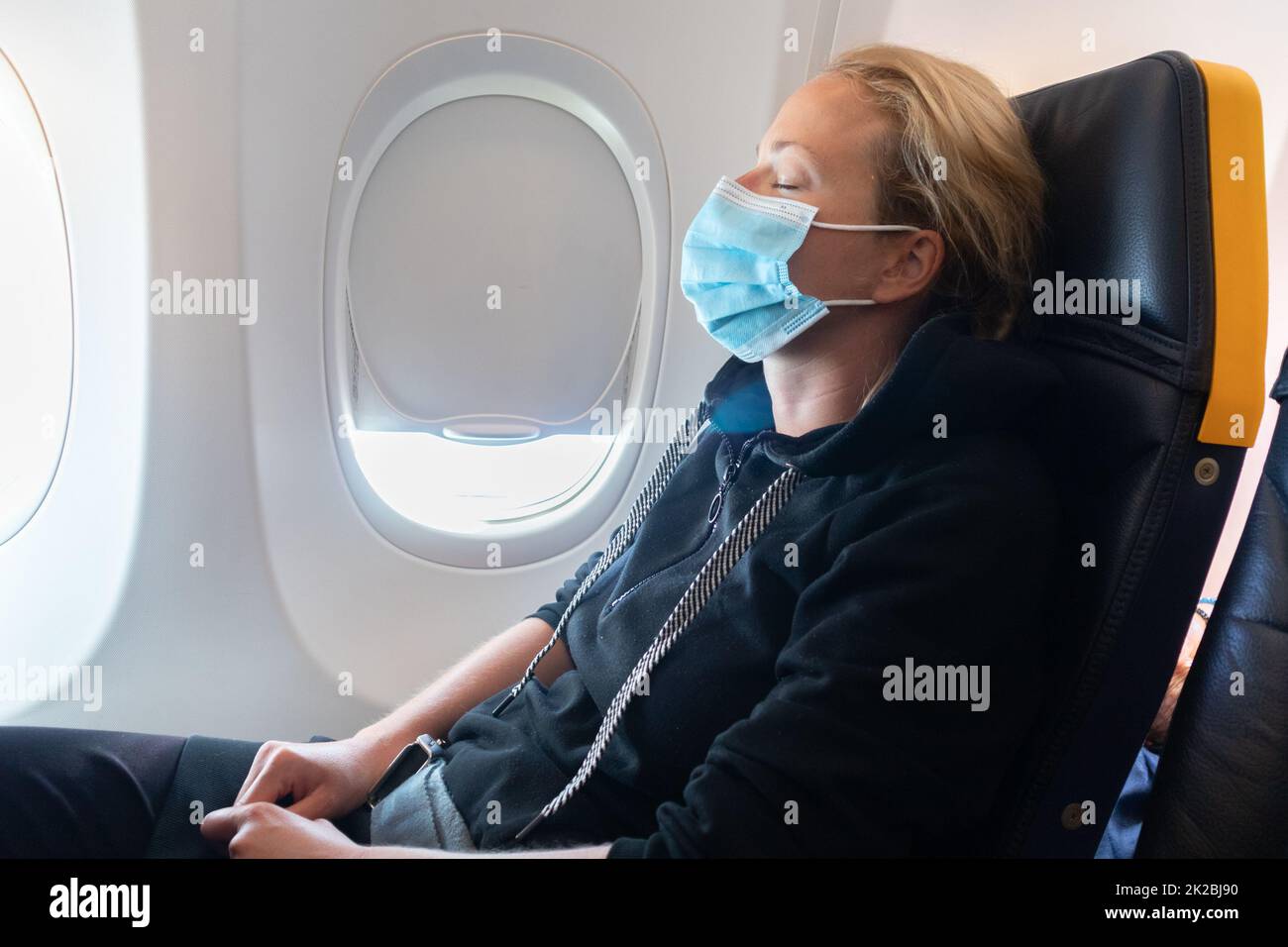 A young woman wearing face mask is traveling on airplane , New normal ...