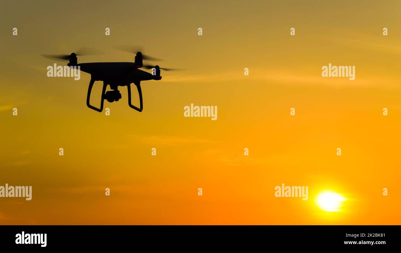 Quadrocopters silhouette against the background of the sunset. Flying ...