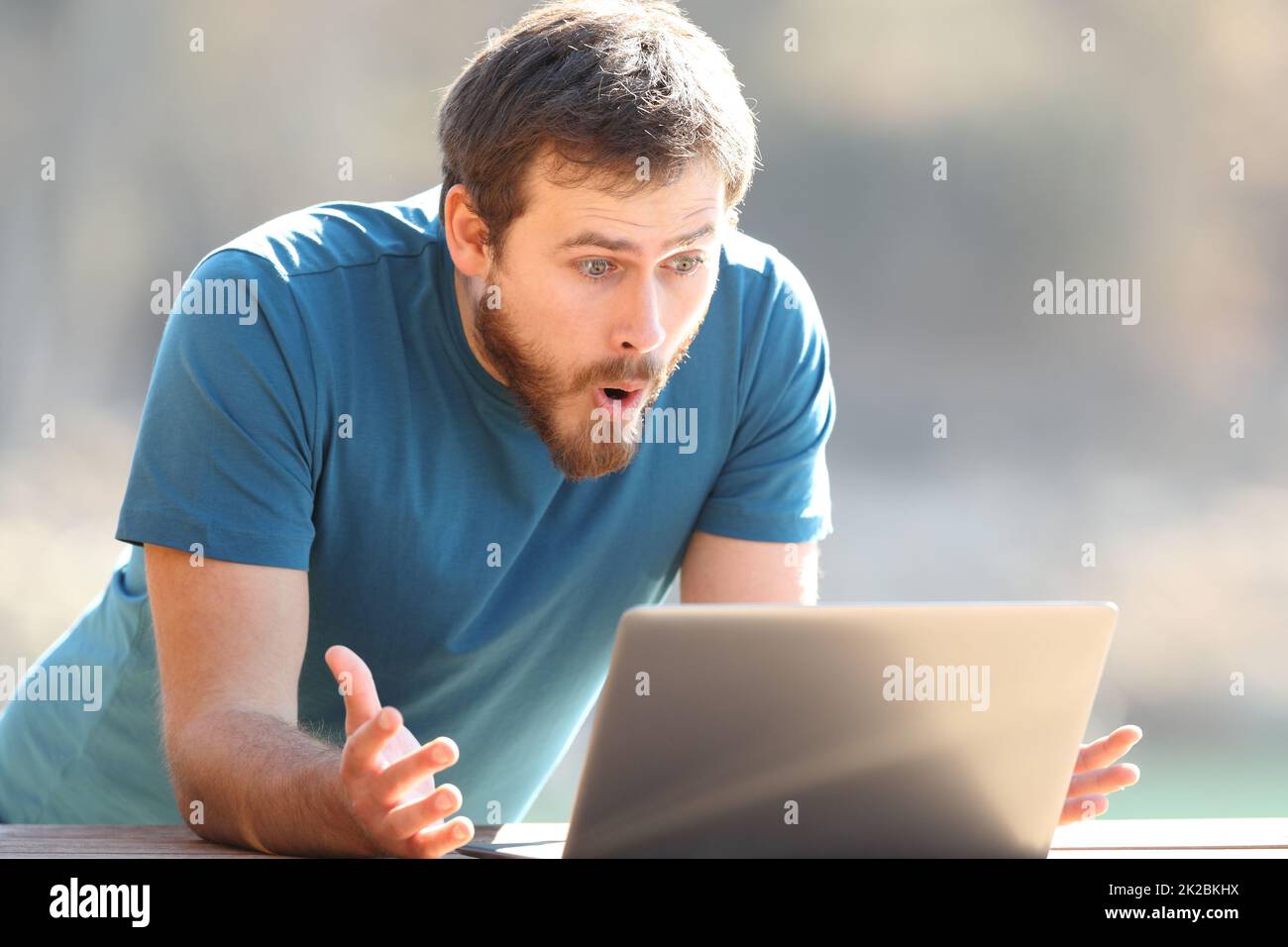 Amazed man checking laptop content outdoors Stock Photo - Alamy