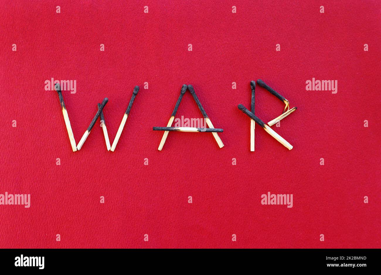 Burnt matches forming the word WAR on a red paper background Stock ...
