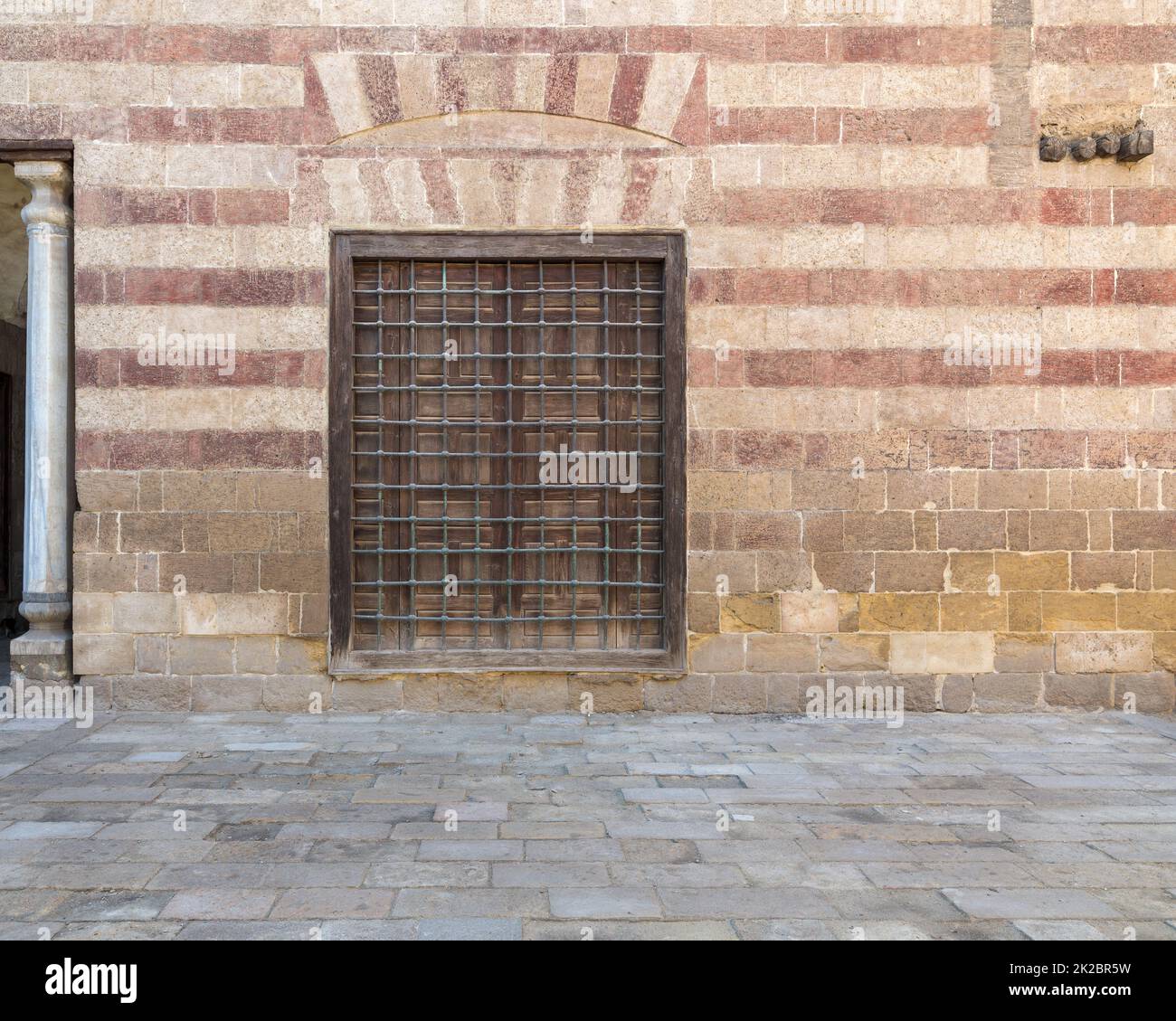 Wooden window with decorated iron grid over stone bricks wall Stock ...