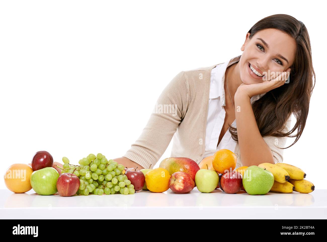 Enjoy natures bounty. A smiling young woman sitting beside a selection ...