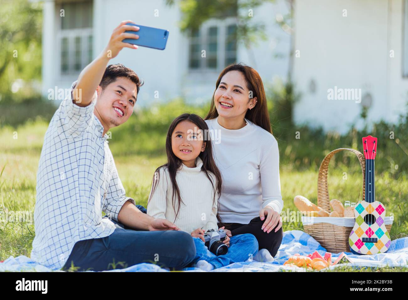 Happy family having fun outdoor sitting on picnic blanket taking selfie ...
