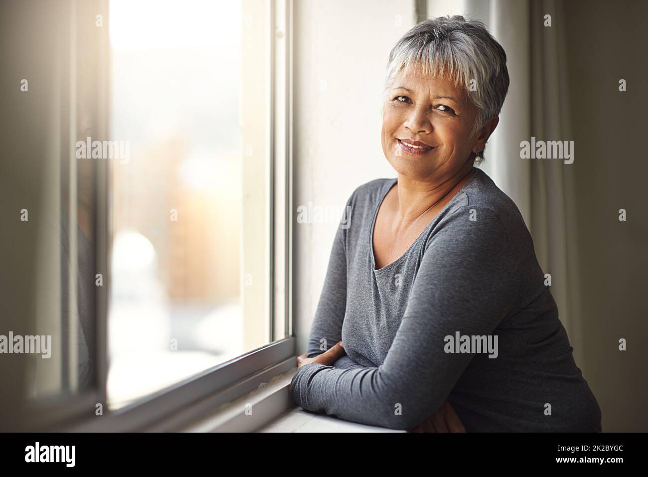 Happy mature woman by the window hi-res stock photography and images ...