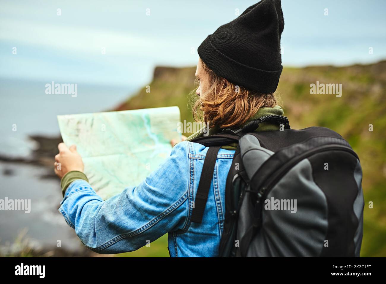 Finding my way through nature. Shot of a young man looking at a map for ...