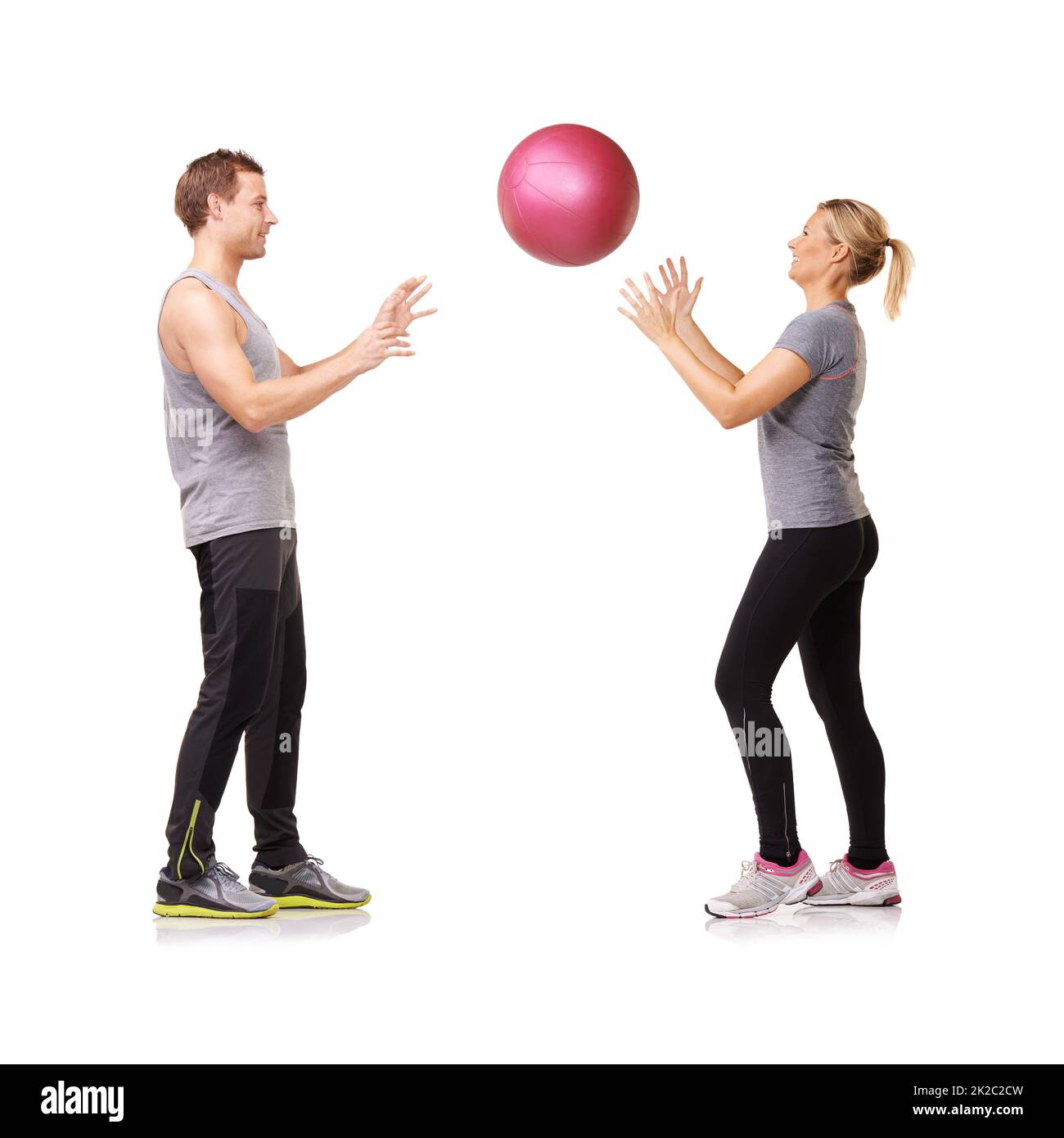 Getting fit together. A man and woman exercising by throwing a medicine ...