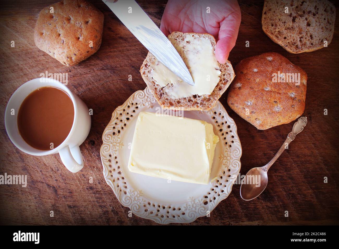 Women hand with a knife spreads butter on bread .Breakfast background ...