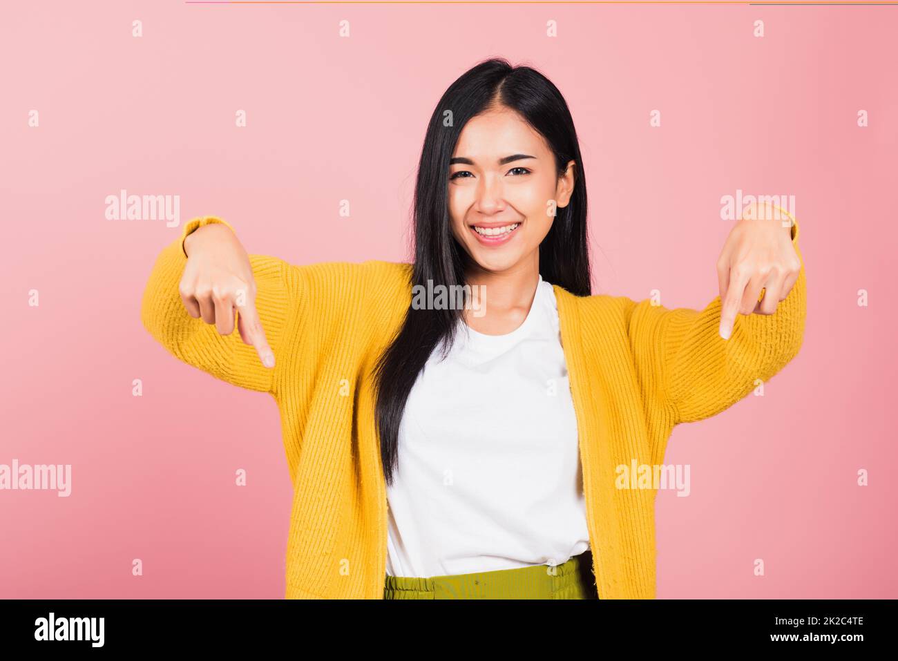 woman smiling stand makes gesture two fingers pointing below down ...