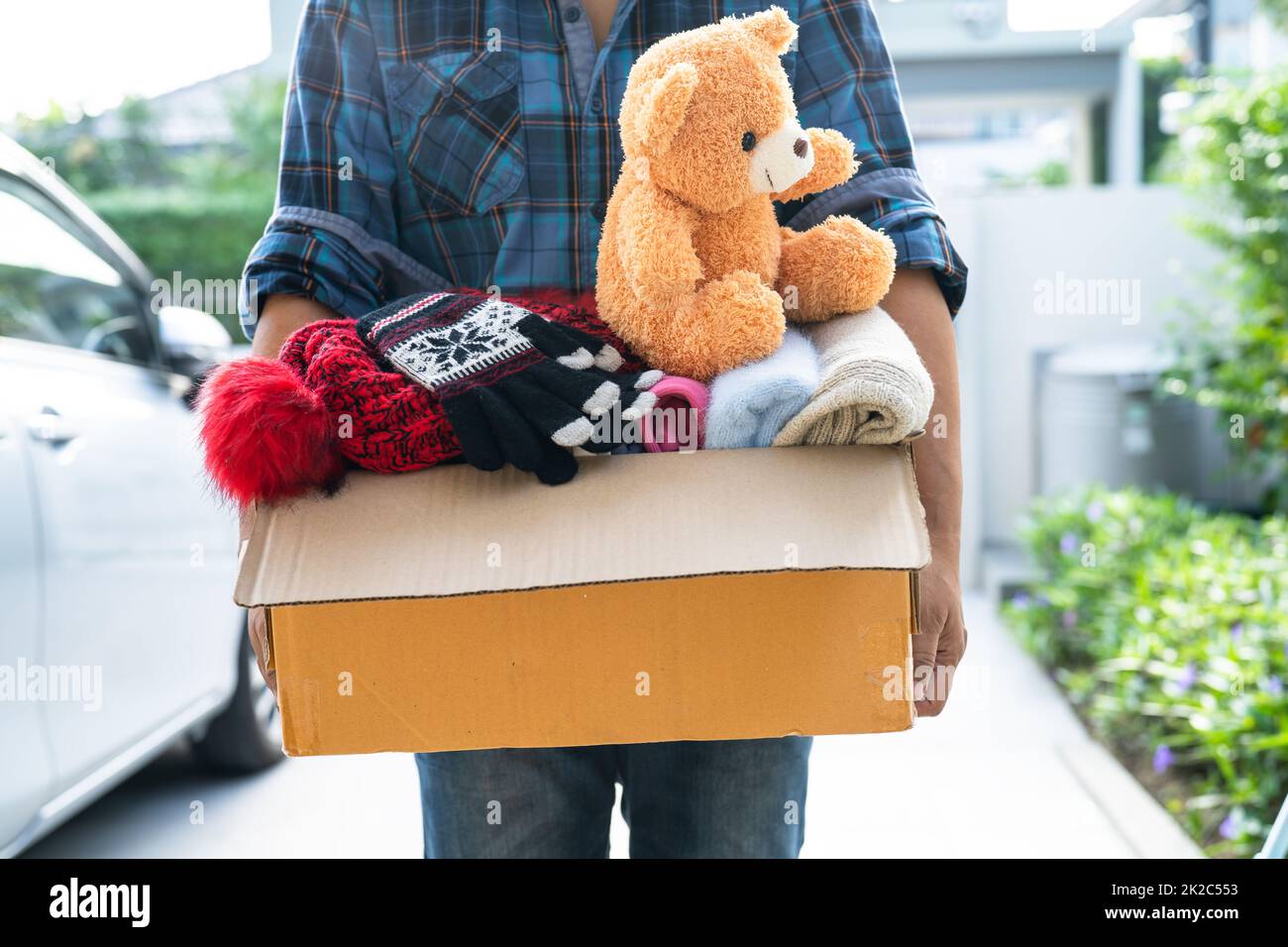 Holding clothing donation box with used clothes and doll at home to ...
