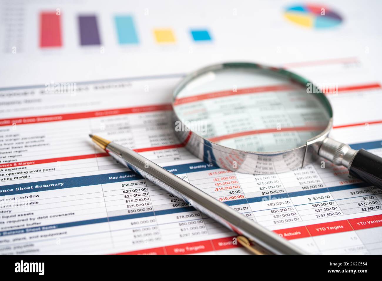 Magnifying glass on charts graphs spreadsheet paper. Financial ...
