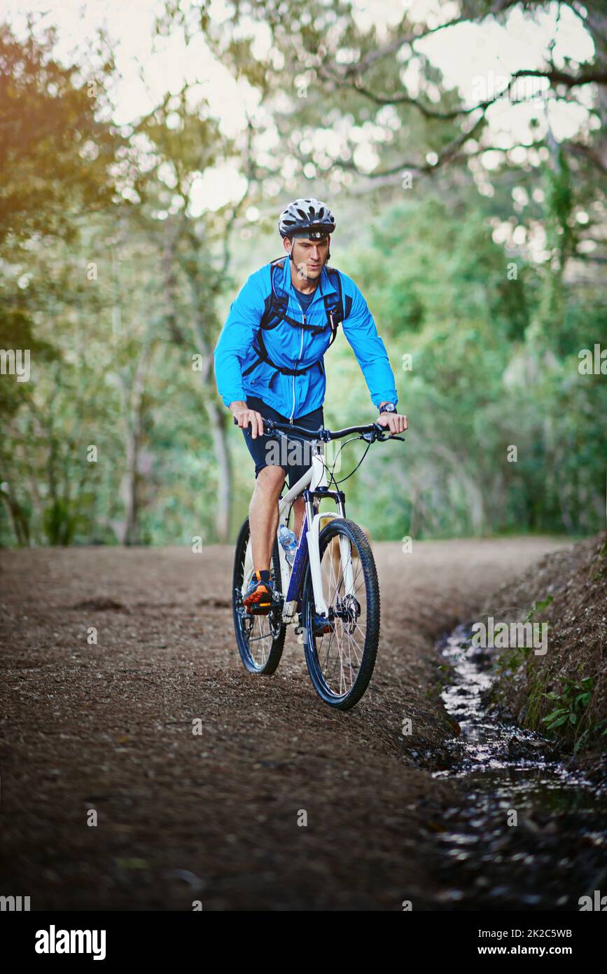 Keeping fit and enjoying nature. Shot of a male cyclist riding along a ...