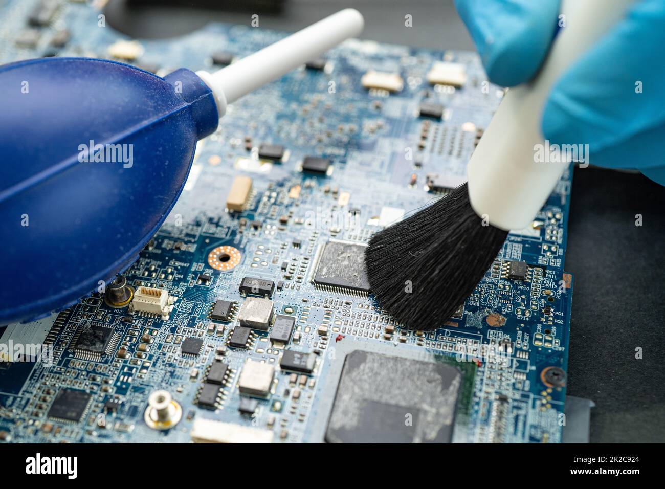 Technician use brush and air blower ball to clean dust in circuit board ...