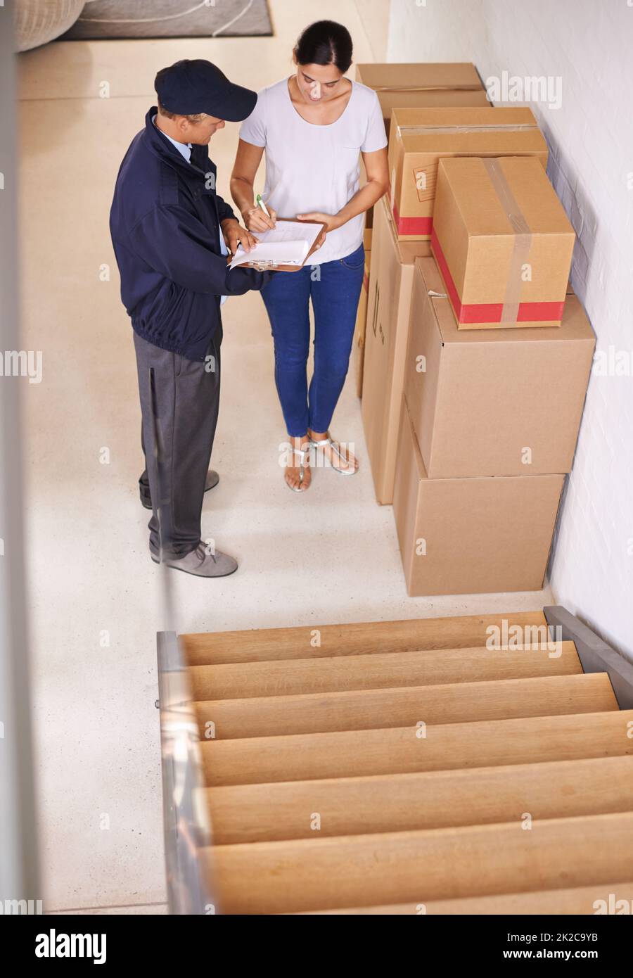 Sign here please..... A young woman receiving a package from a delivery ...