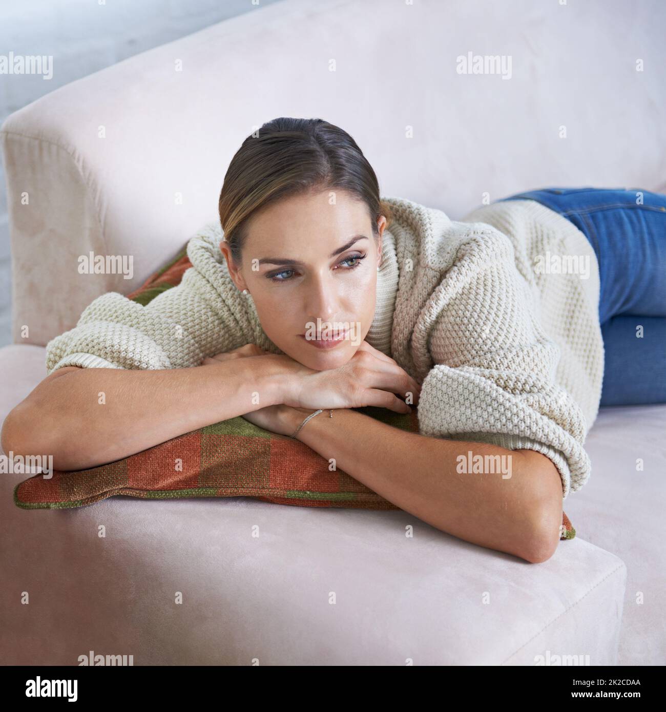 Deep in thought. Portrait of a beautiful young woman lying on her couch ...