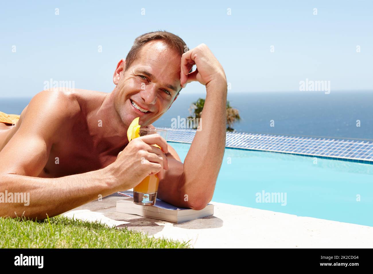 Relaxing by the pool. Portrait of a smiling man enjoying the sunshine ...