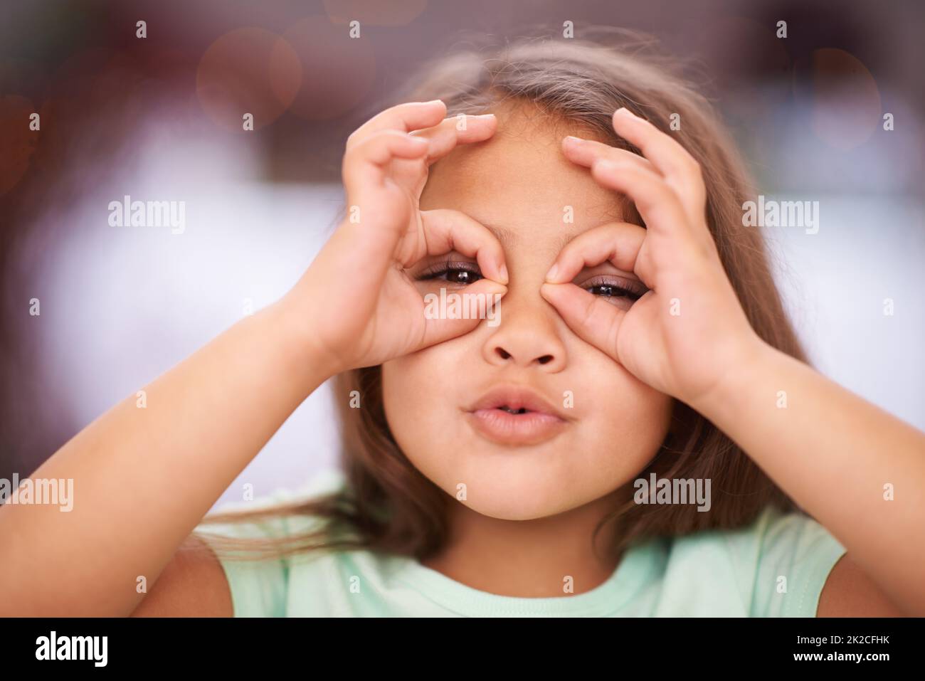 I see you. Shot of a playful little girl with pulling a funny face ...