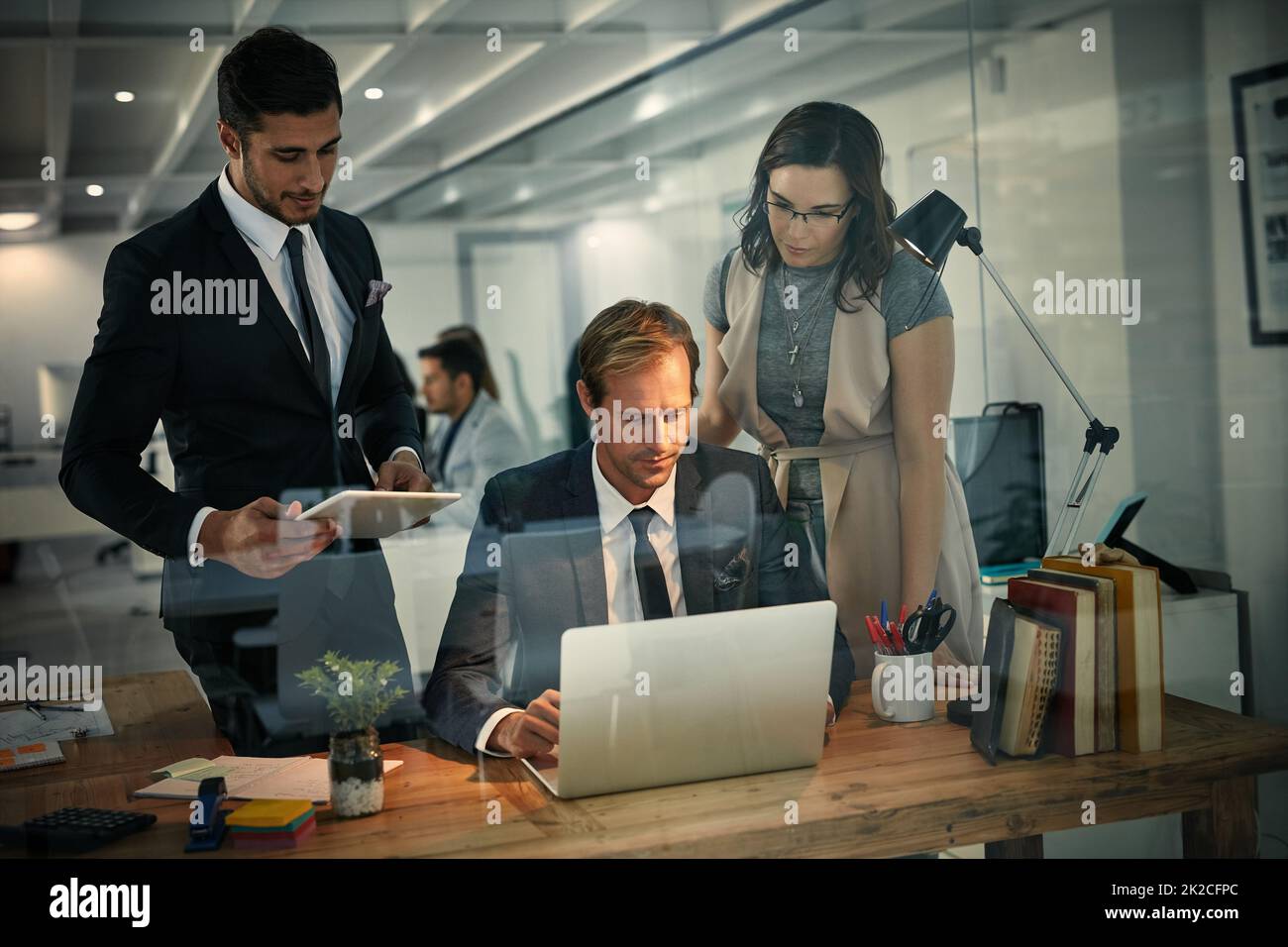 Increasing productivity with teamwork and extra hours. Shot of a team ...