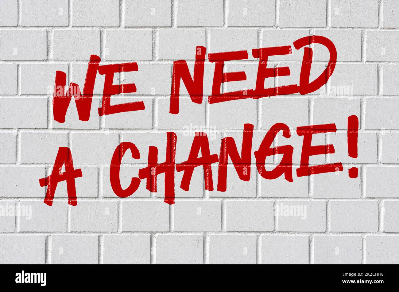 Graffiti on a brick wall - We need a change Stock Photo - Alamy