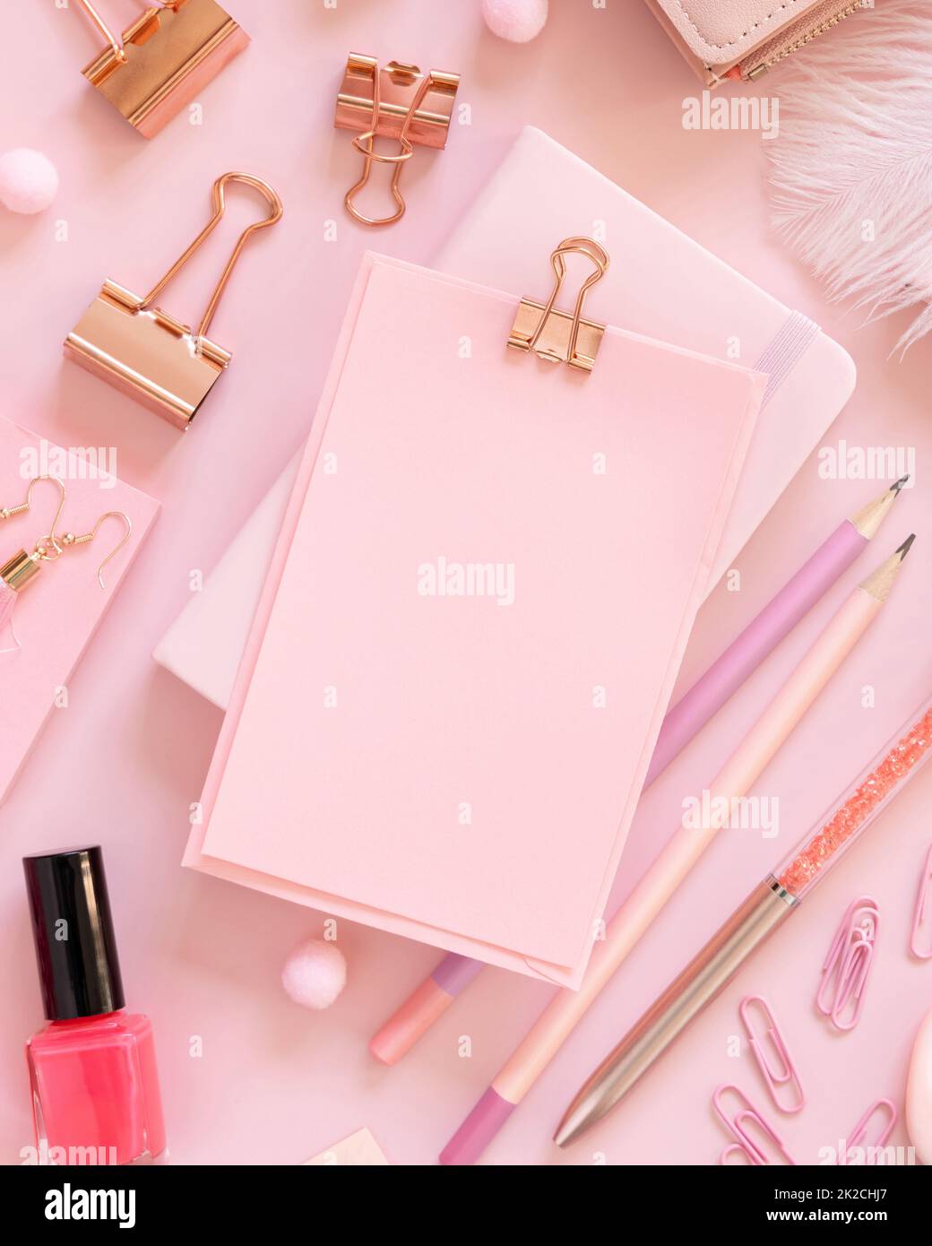 Paper with a clip and Pink girly accessories on pastel pink Top view ...