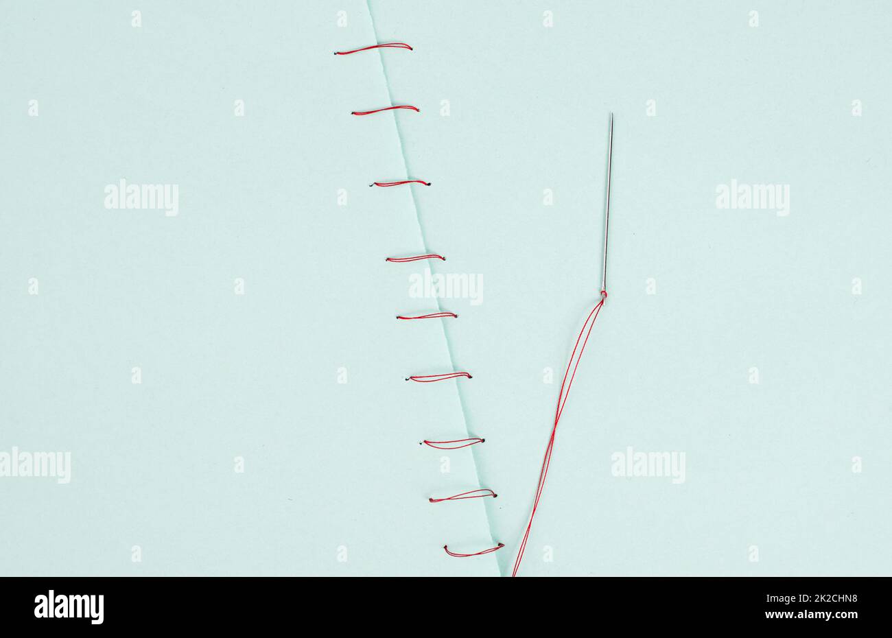 Two pieces of torn paper sewn together with a red string, financial ...