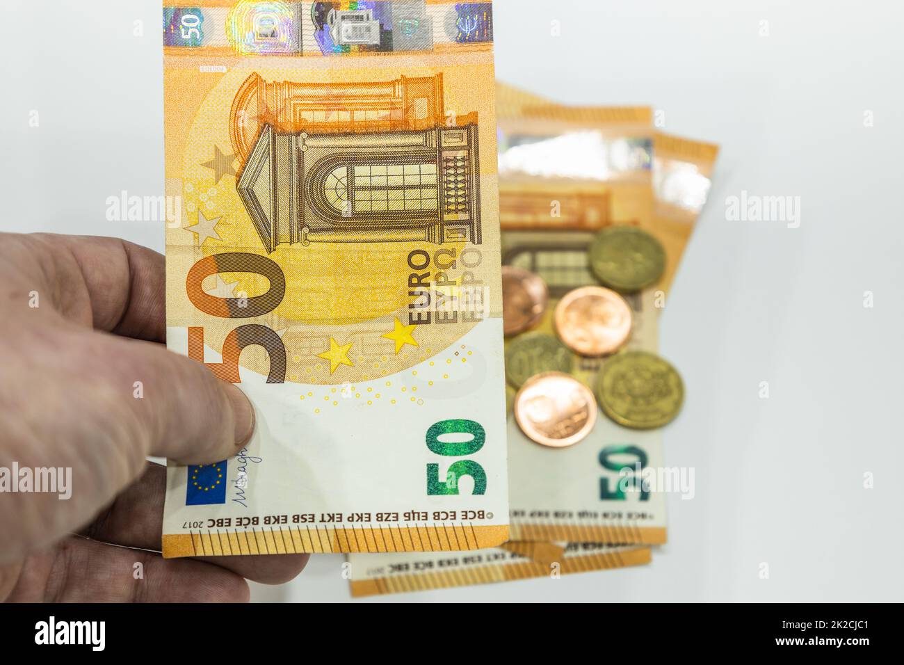 Male hand holding 50 Euro note and coins in the background Stock Photo ...