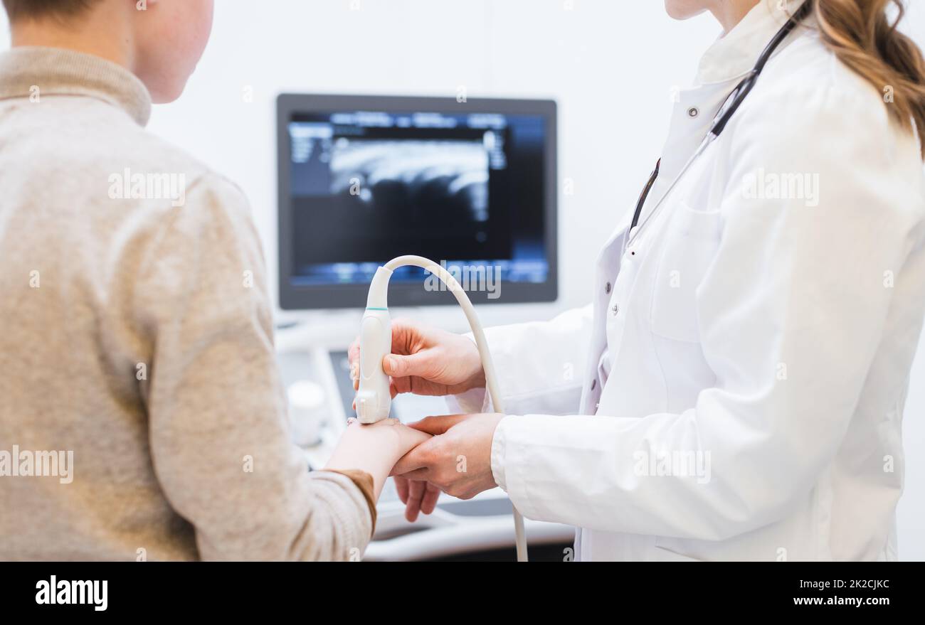 Doctor doing ultrasonic scan on hand of boy Stock Photo - Alamy