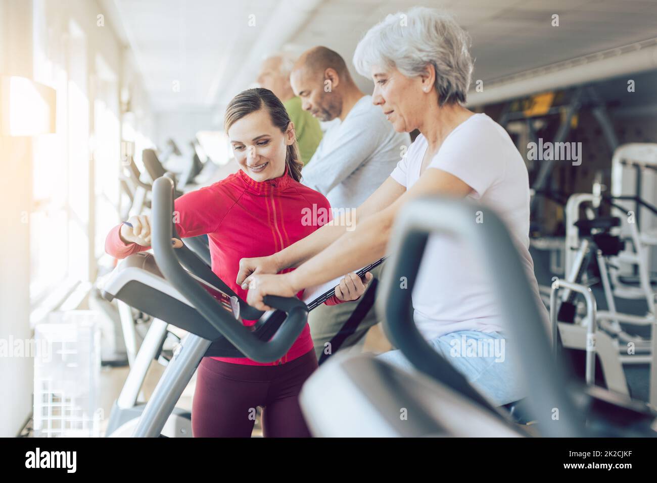Fitness coach in gym helping senior people Stock Photo - Alamy