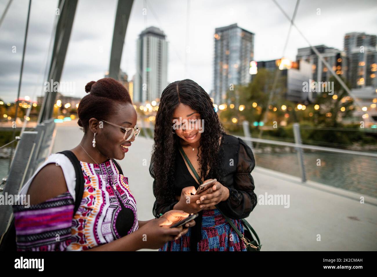 Young women friends texting with smart phones on city bridge Stock ...