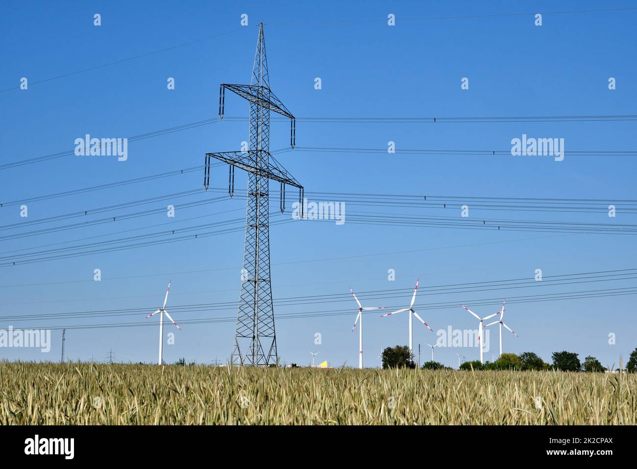 Electricity pylon with power lines and wind turbines in the background ...