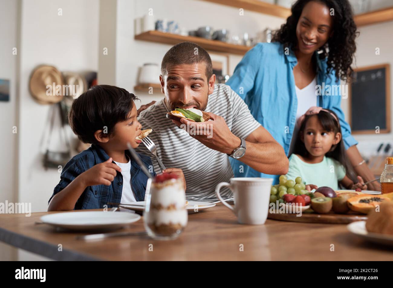 The boy just cant resist a good breakfast. Shot of a family of four ...