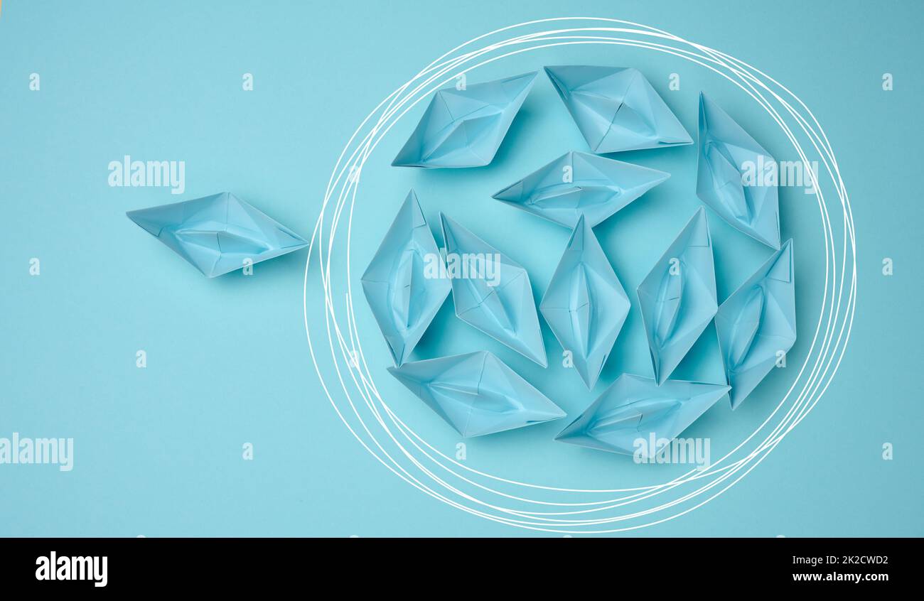 group of paper boats floats in a circle, another red floats in a ...