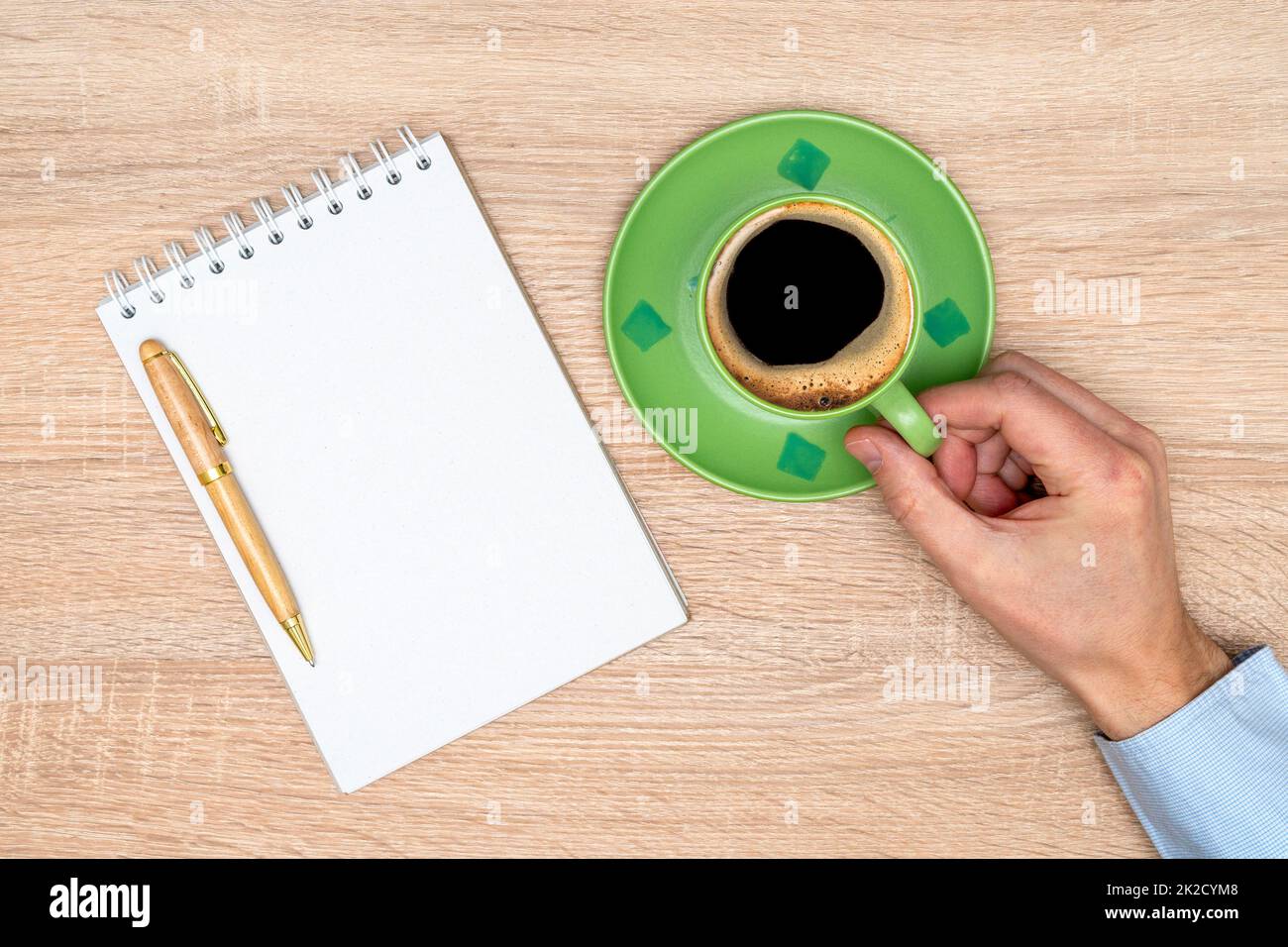 Hand with cup of coffee in the office with notebook Stock Photo - Alamy