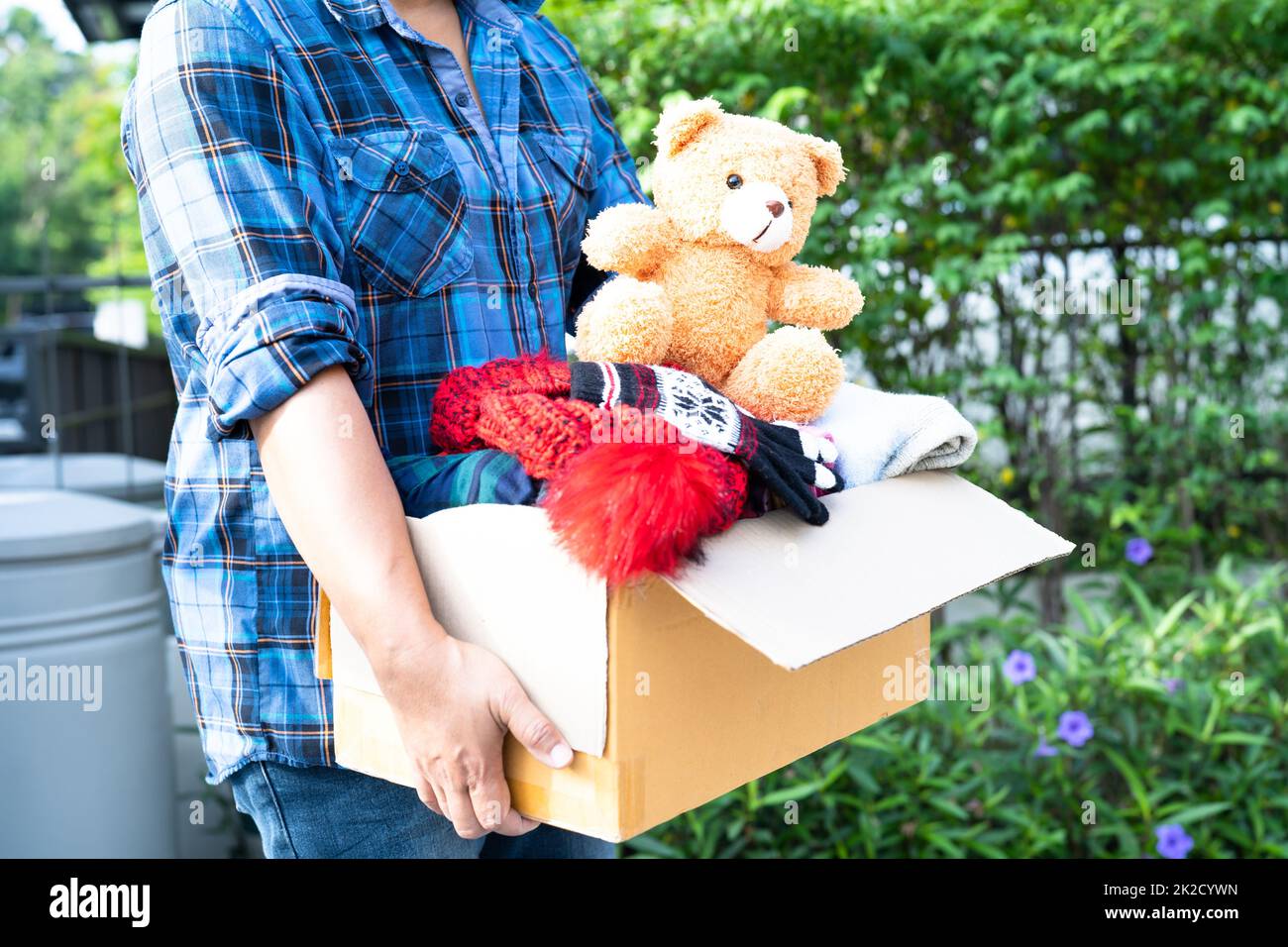 Holding clothing donation box with used clothes and doll at home to ...
