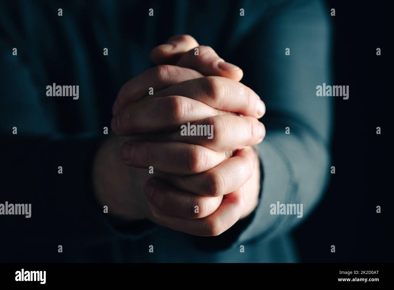 Man hands in praying position low key image Stock Photo - Alamy