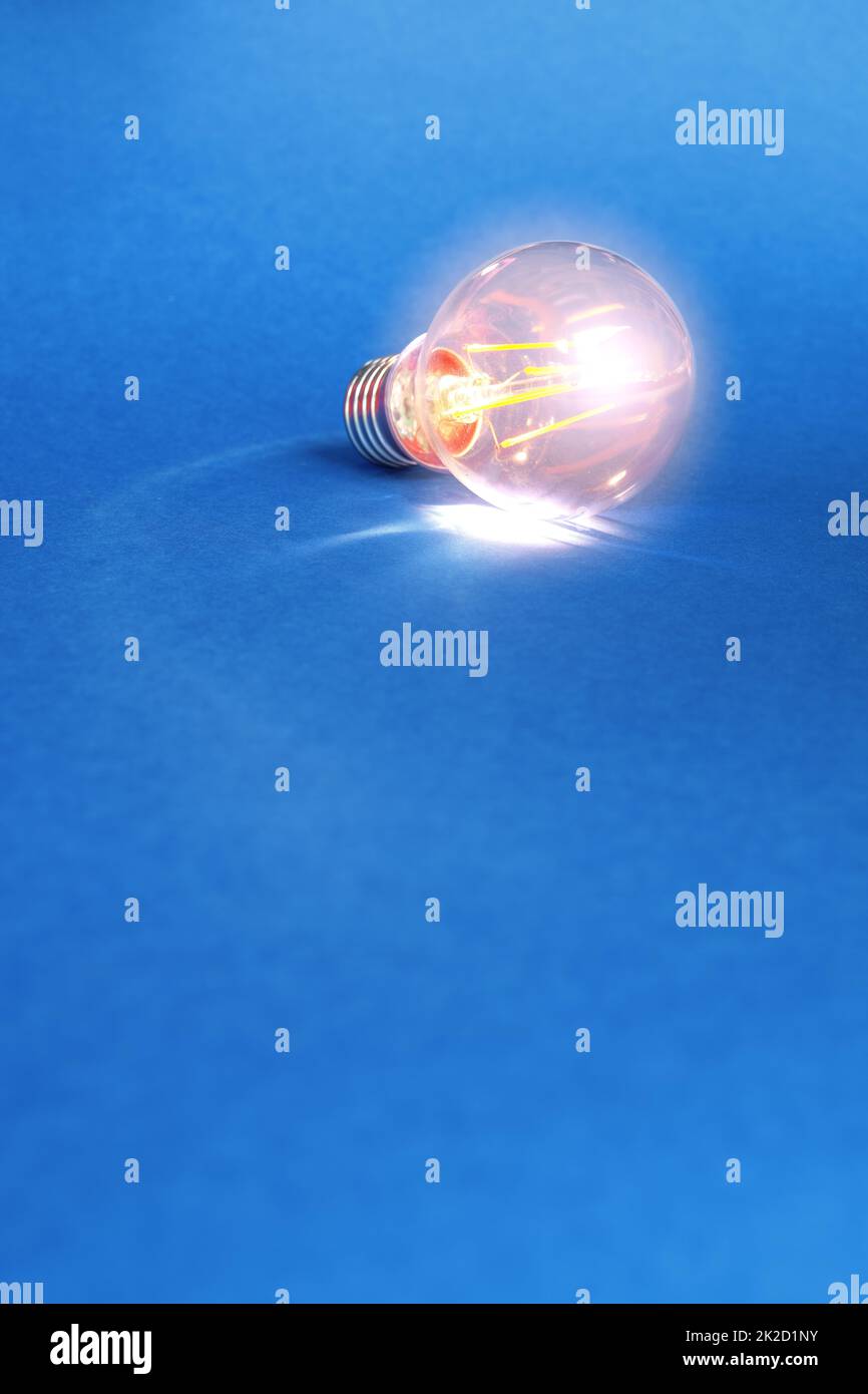 Single light bulb with light inside on blue background with copy-space ...