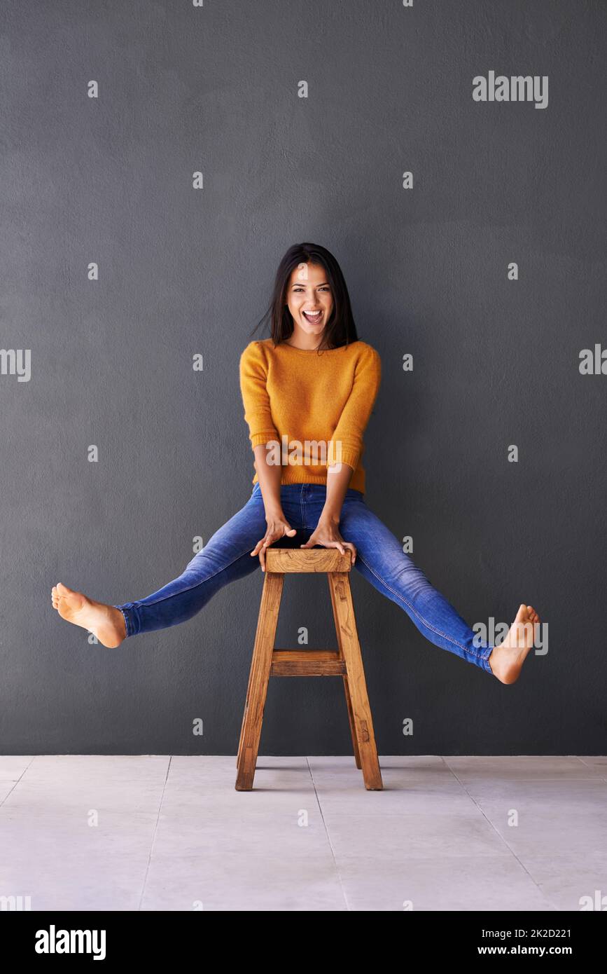 Feel like a kid again. An attractive young woman sitting playfully on a ...