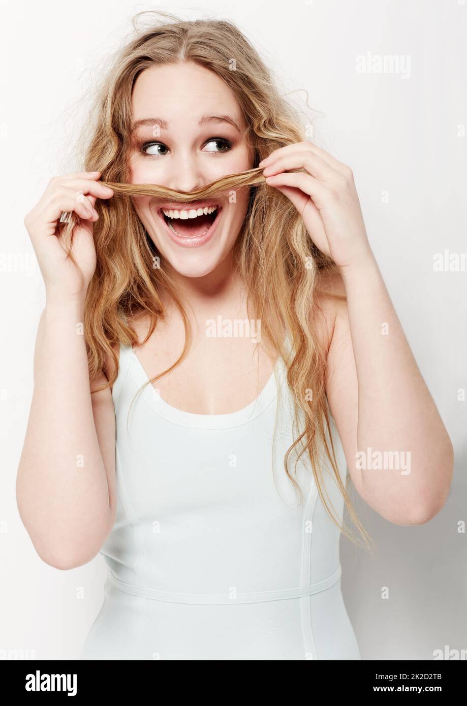 Having fun. Playful young woman making a mustache with her hair against a white background Stock ...