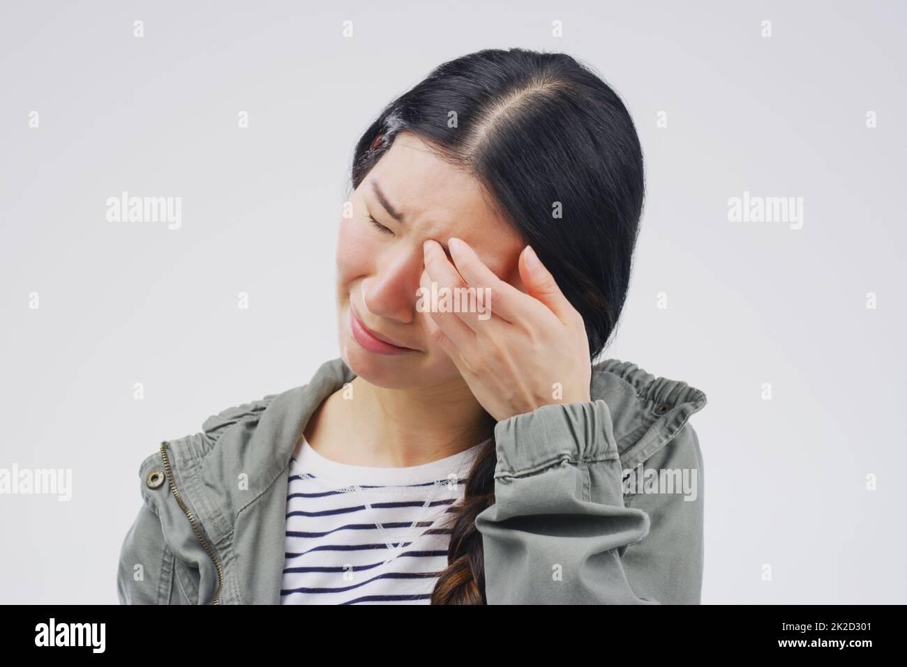 I have something in my eye. Studio shot of a young woman crying while ...