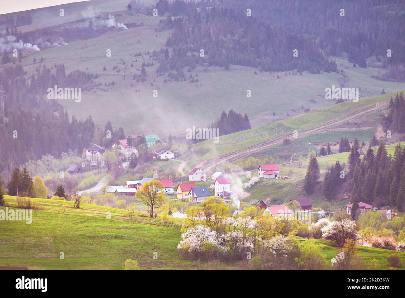 spring landscape. Blooming garden flower trees. Traditional mountain village on hills. Orchard ...