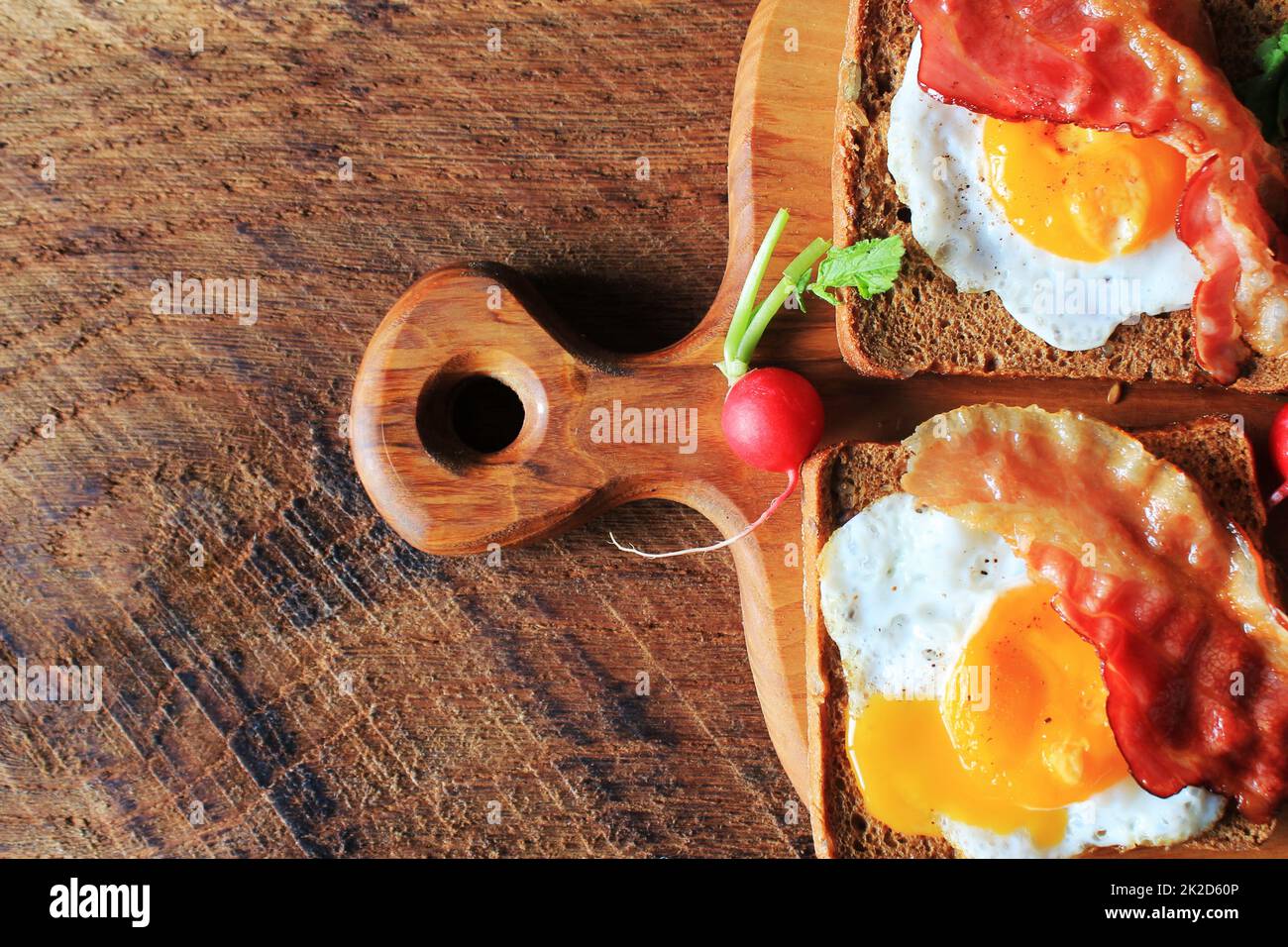 Breakfast of crispy bacon, fried eggs and bread. Sandwiches on cutting ...